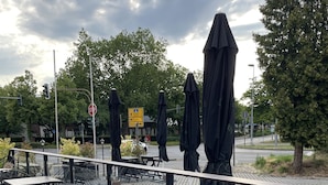 Mobiliário de exterior com mesas e cadeiras, guarda-sóis e uma placa de stop ao fundo.