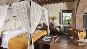 Quarto com cama de dossel, móveis de madeira e vista para o verde lá fora.
