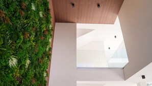 Um interior moderno com teto alto, parede de vidro e uma parede verde exuberante.