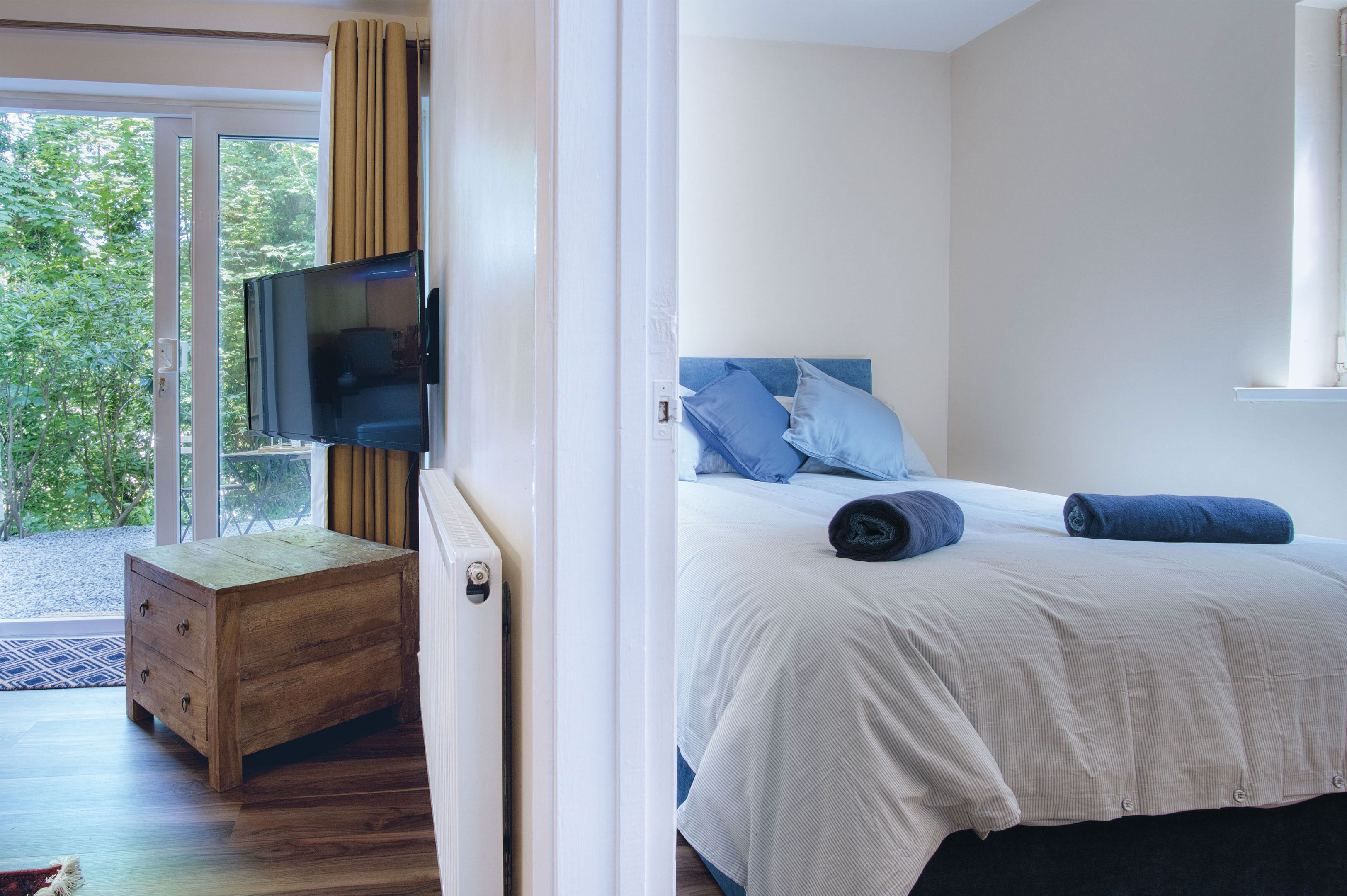 Um quarto com uma cama, uma televisão e uma mesinha de cabeceira de madeira.