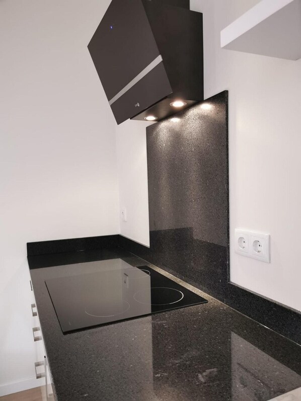 Uma cozinha moderna com bancada preta, fogão embutido e backsplash elegante.