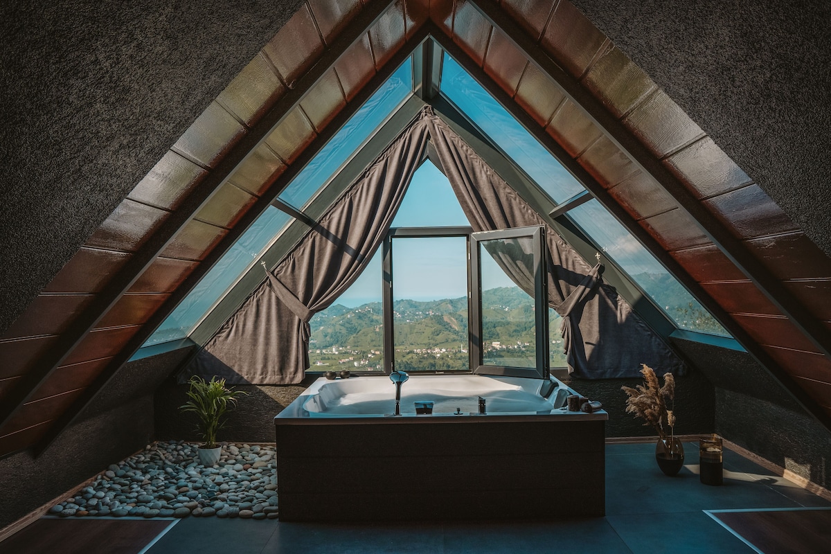 Um banheiro moderno com um amplo claraboia, uma banheira e vista para as montanhas.