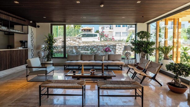 Uma sala de estar moderna com parede de pedra, um sofá, duas poltronas, uma mesa de centro e uma mesa de jantar.