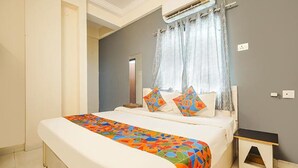 Quarto com cama, almofadas coloridas, mesa de cabeceira e uma casinha para animais de estimação.