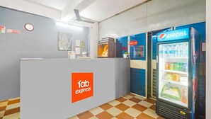 Um espaço de lobby com uma recepção identificada como 'fab express', um refrigerador de Pepsi e um relógio na parede.