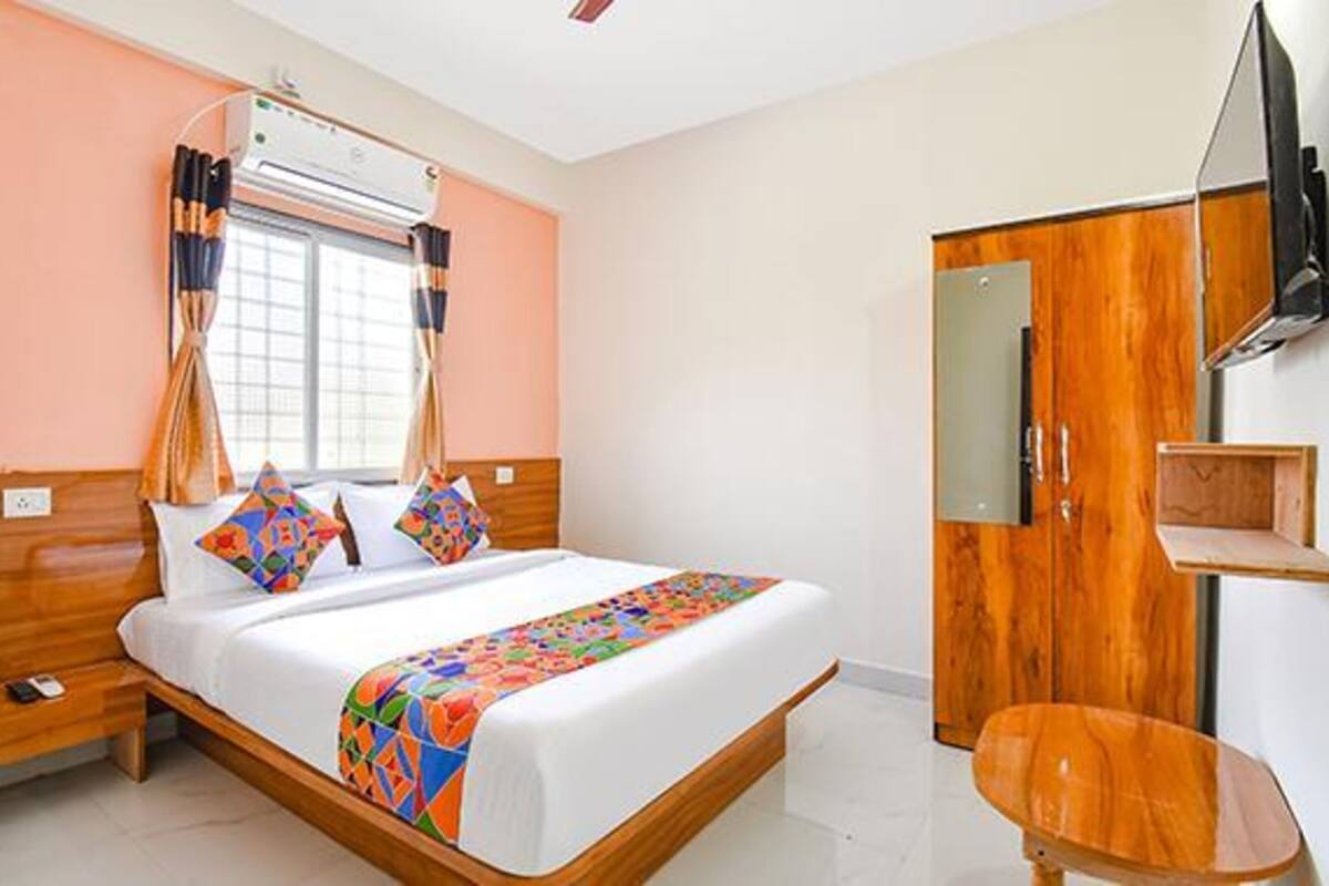 Quarto com cama de madeira, televisão fixada na parede e guarda-roupa.