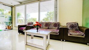Uma sala de estar ampla com uma grande janela, um conjunto de sofás e uma mesa de centro.