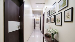 Um corredor com uma porta de madeira, um painel branco e uma mesa com um vaso de flores.