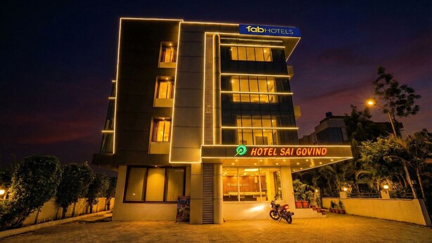 Um hotel moderno com uma placa que diz 'fabHOTELS' e 'HOTEL SAI GOVIND'.