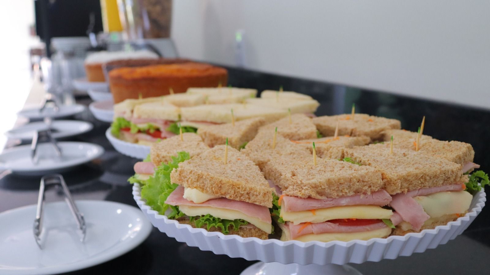 Uma mesa de buffet com sanduíches e um bolo.