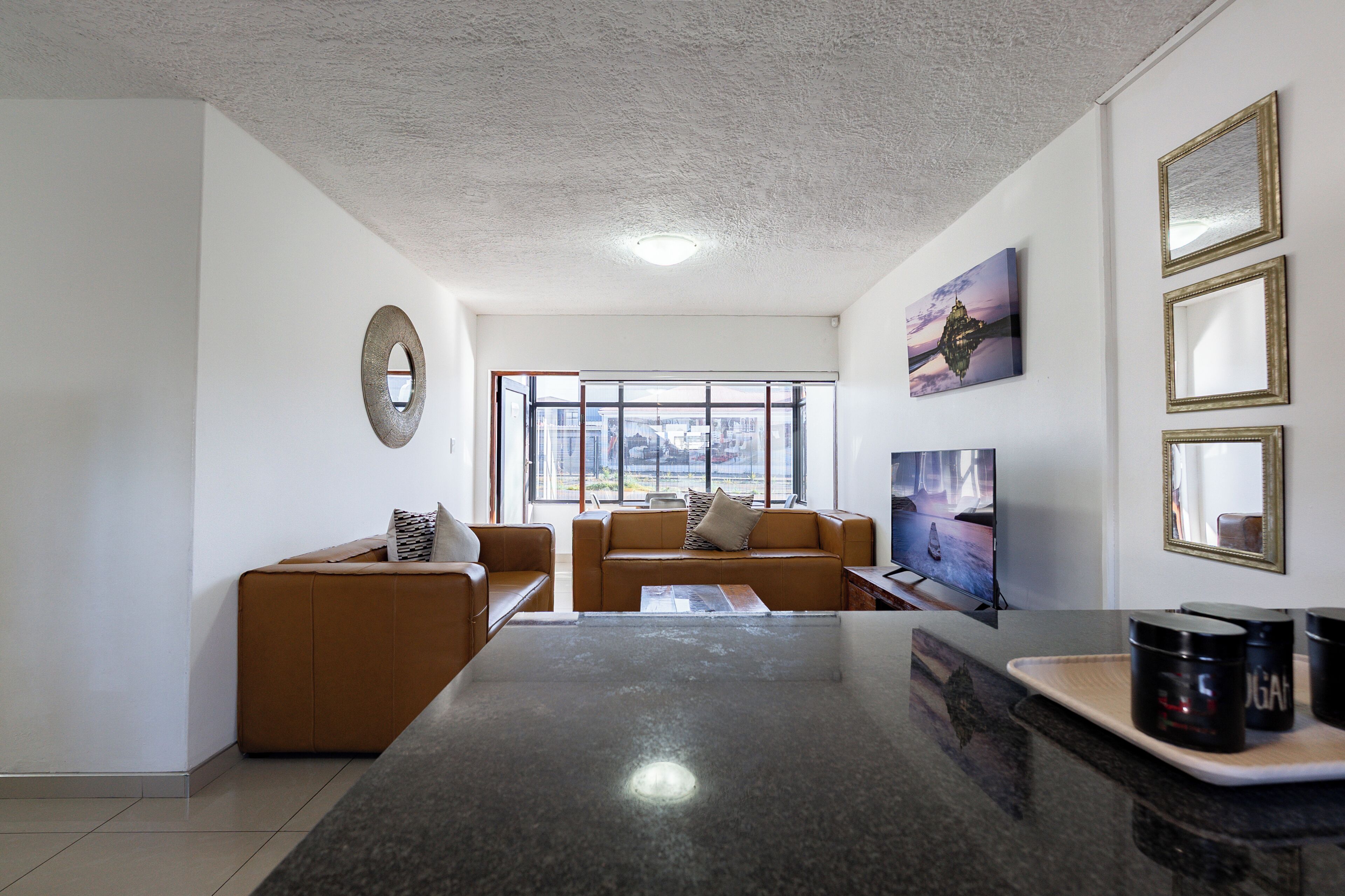 Uma sala de estar moderna com sofá, mesa de centro, TV e uma janela grande.
