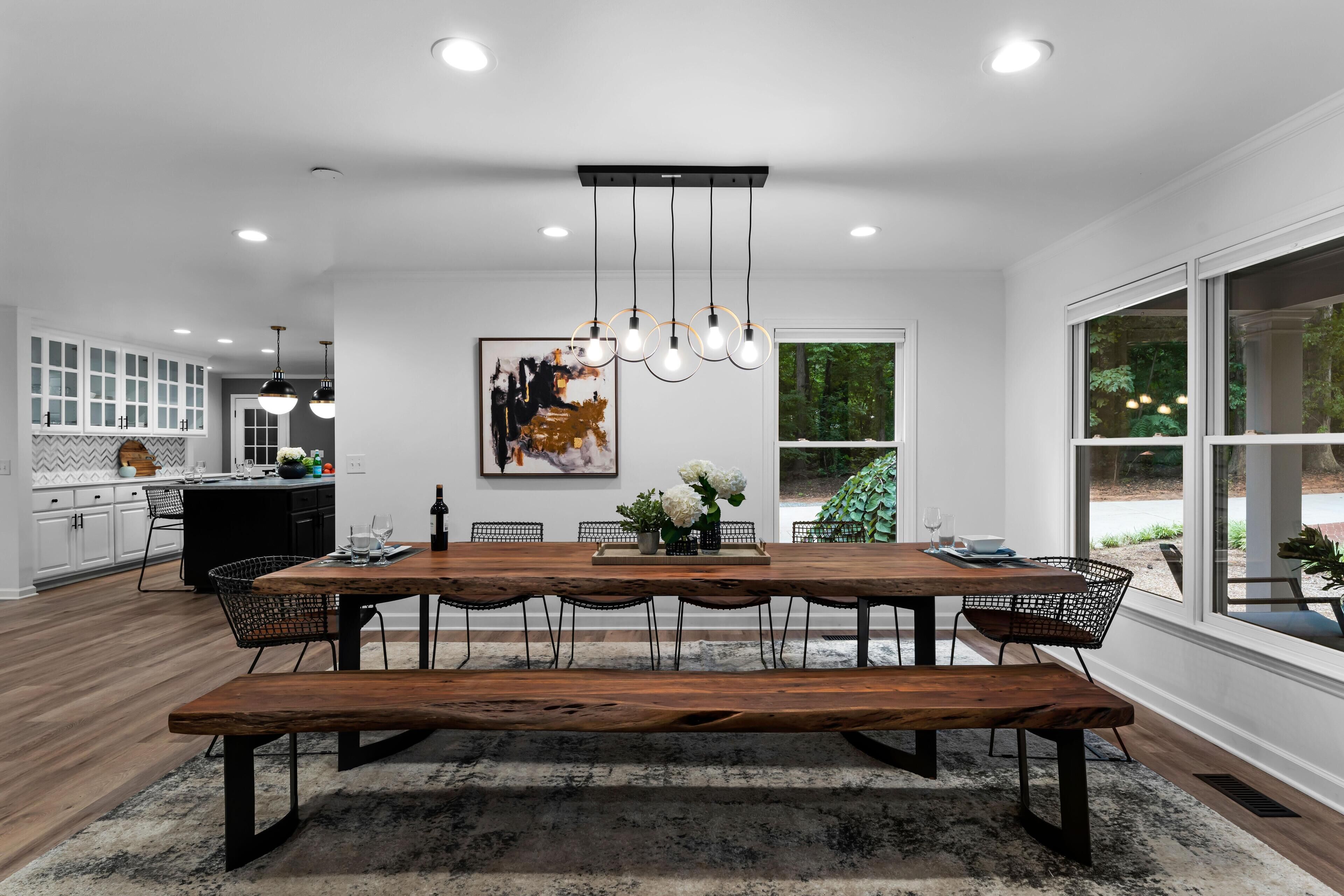 Uma sala de jantar moderna com uma mesa de madeira e bancos, rodeada por cadeiras.