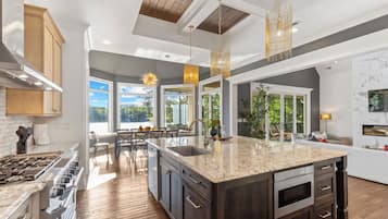 Uma cozinha ampla com uma ilha grande, armários de madeira e um lustre moderno.