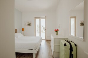 Quarto com cama, cômoda, espelho e mala.