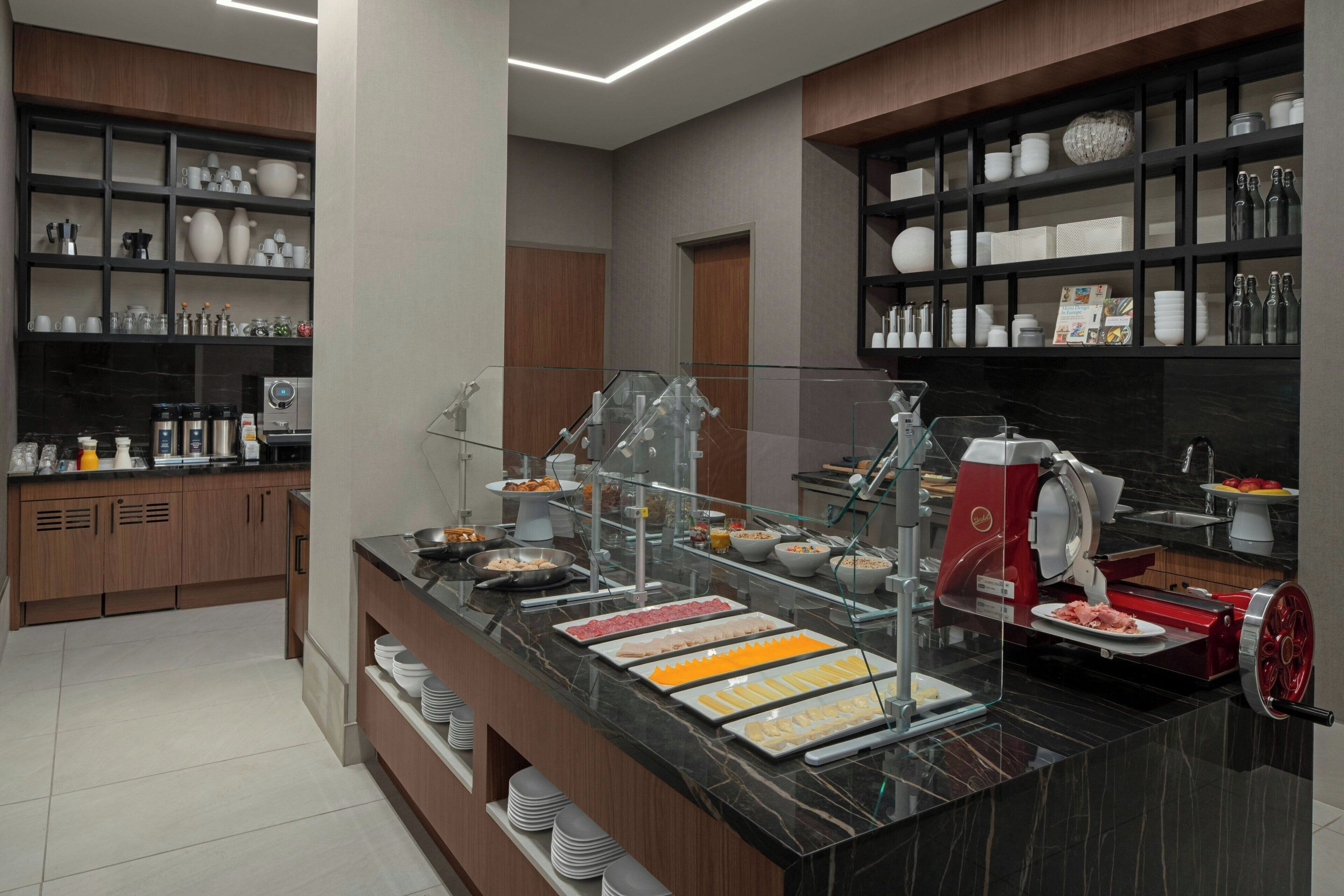 Cozinha moderna com bancada de mármore, vitrine de vidro e um fatiador de carne.