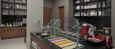 Cozinha moderna com bancada de mármore, vitrine de vidro e um fatiador de carne.