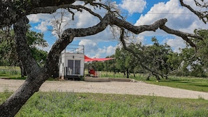 Um edifício com toldo vermelho, rodeado por árvores e um caminho de cascalho.