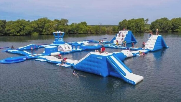 Um parque aquático ao ar livre com diversas estruturas infláveis e escorregadores.
