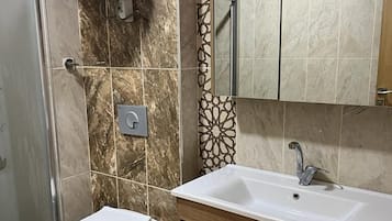 Apartamento Deluxe | Casa de banho | Um polibã, um chuveiro fixo, um secador de cabelo, chinelos