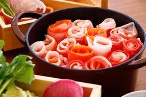 Uma panela cheia de fatias de carne bem enroladas, provavelmente para uma demonstração culinária ou buffet.