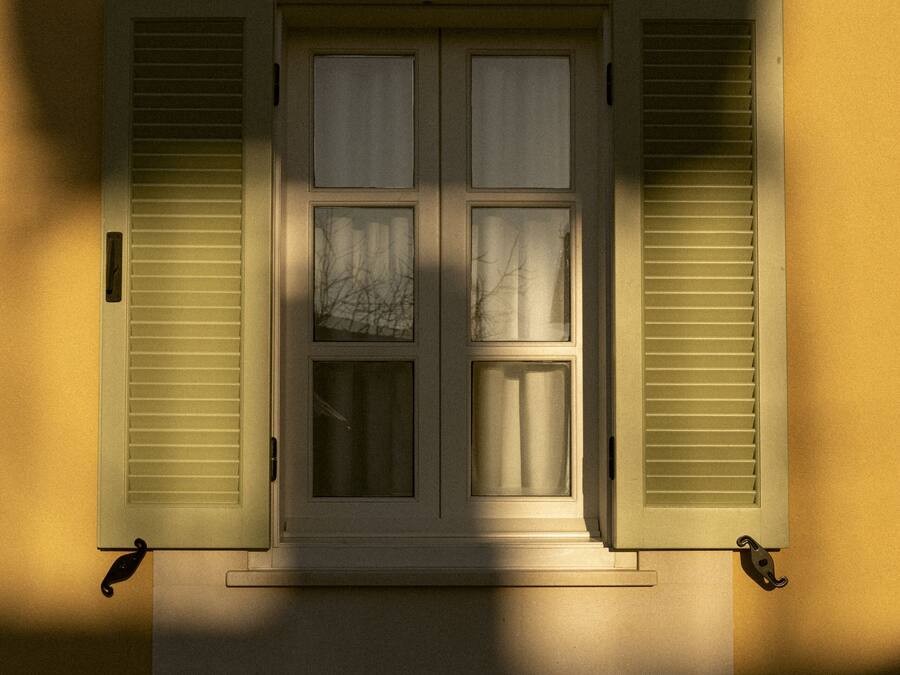 Uma janela com persianas, uma porta e uma parede.