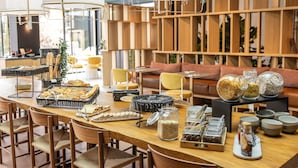 Um buffet de café da manhã com diversos alimentos e uma área de estar com sofá e cadeiras.