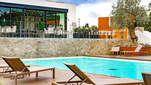 Uma área à beira da piscina com espreguiçadeiras e um muro de pedra.