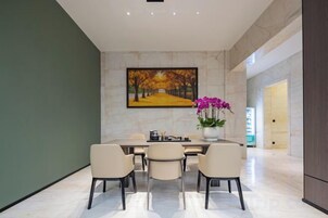 Uma área de refeições moderna com parede de mármore, uma pintura e um vaso de flores.