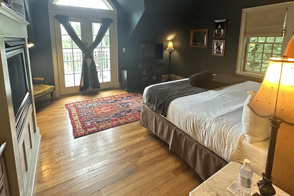 Quarto com uma cama grande, uma escrivaninha com abajur, televisão e lareira.
