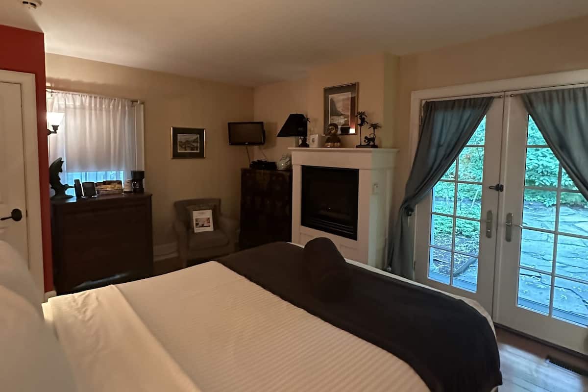 Quarto com cama, penteadeira, televisão e janela com cortinas.