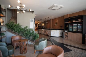 Um hall de hotel moderno com áreas de estar, balcão de recepção e bar.