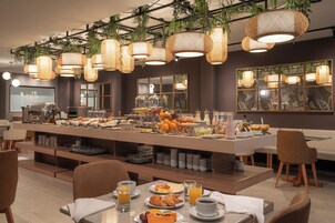 Um buffet de café da manhã com diversos alimentos, luminárias pendentes de vime e design de interiores moderno.