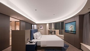 Quarto de hotel moderno com cama, escrivaninha, televisão e vista para a cidade.