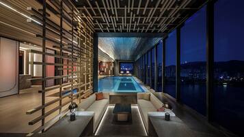 Área moderna de piscina interna com vista para a cidade à noite.
