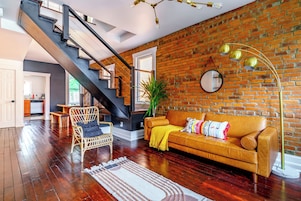 Uma sala de estar moderna com escada, sofá e área de jantar.