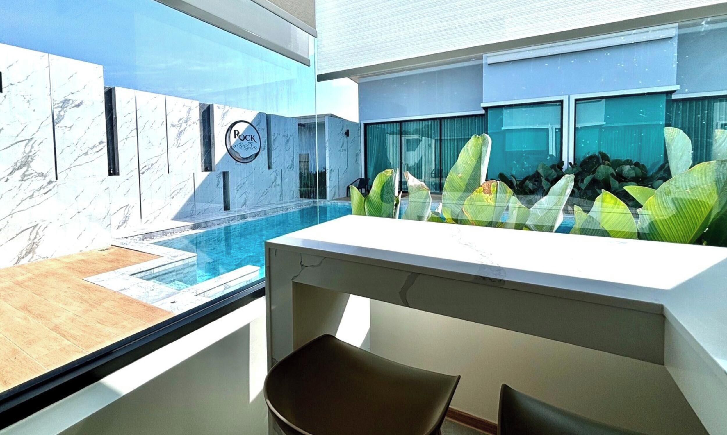 Quarto de hotel moderno com parede de mármore, piscina e vista para o céu.