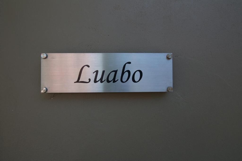 Placa de metal com o nome 'Luabo' fixada na parede.
