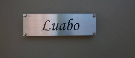 Placa de metal com o nome 'Luabo' fixada na parede.