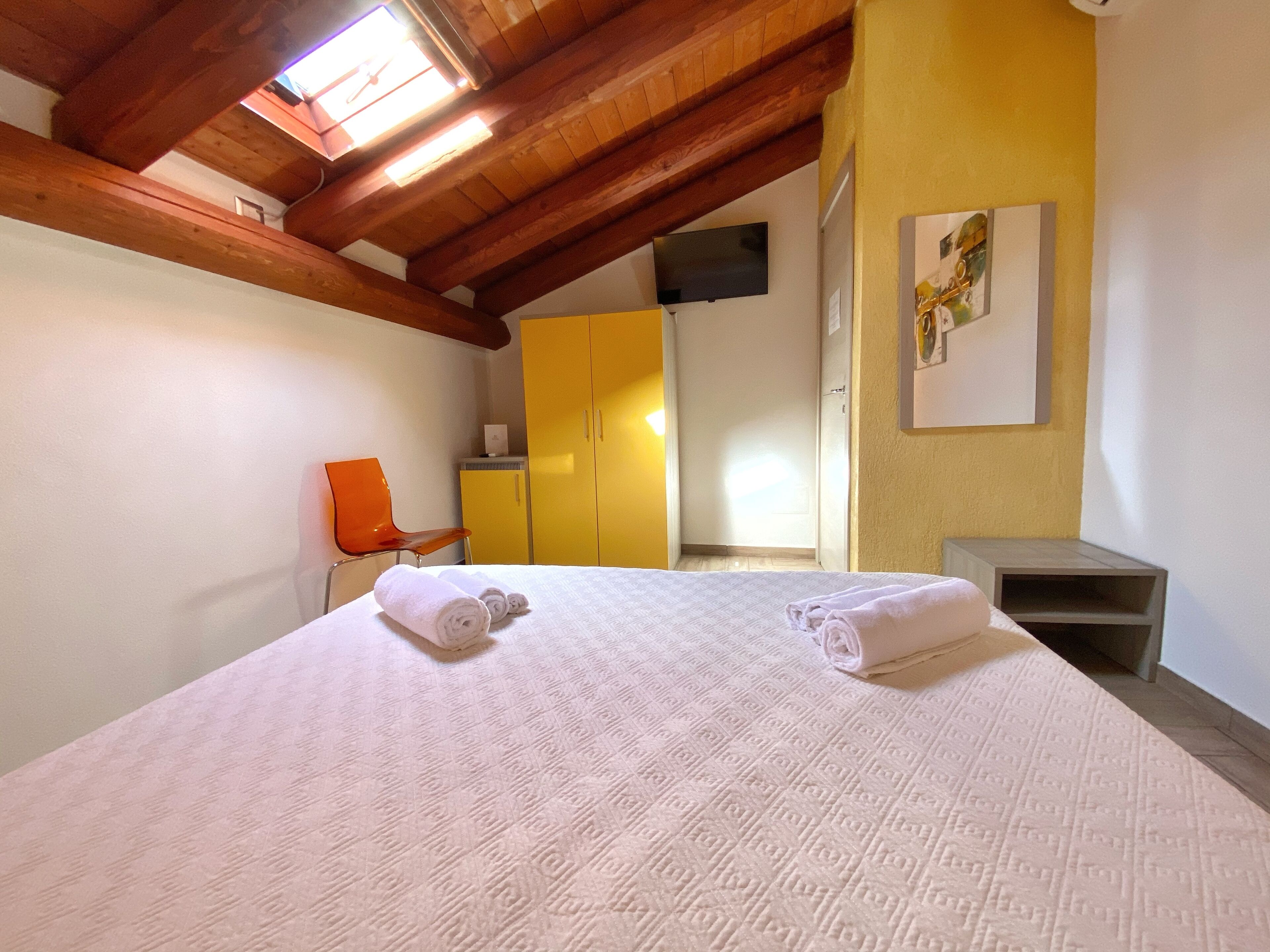 Quarto com cama grande, uma cadeira, um guarda-roupa e um quadro na parede.