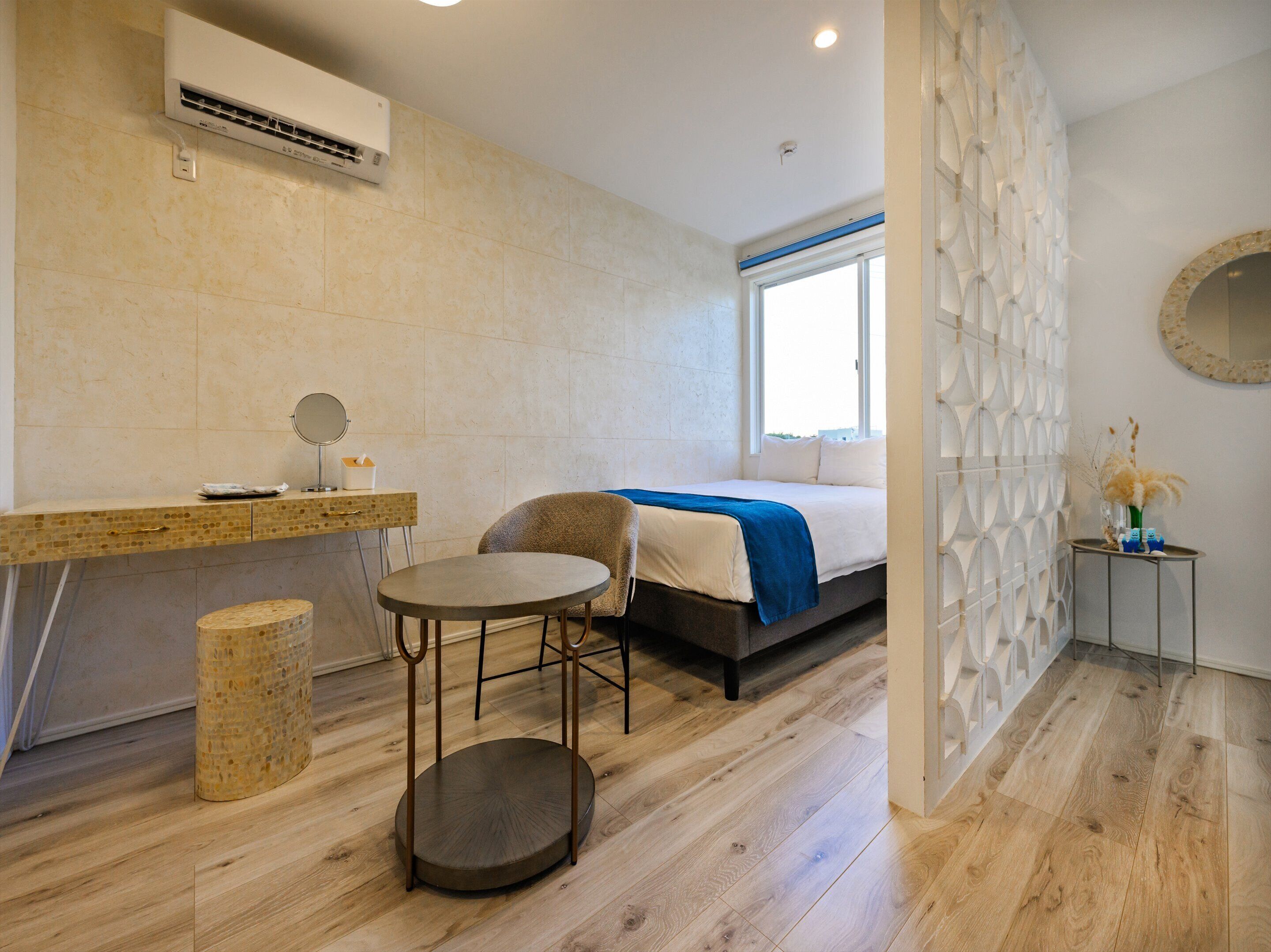 Quarto de hotel moderno com cama, mesa de cabeceira e uma pequena mesa redonda.