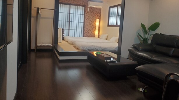 Quarto de hotel moderno com uma cama grande, um sofá, uma pequena mesa e um espelho.
