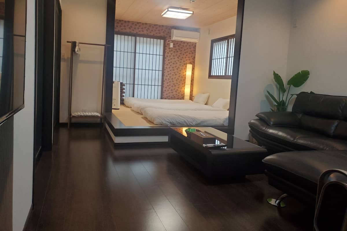 Quarto de hotel moderno com uma cama grande, um sofá, uma pequena mesa e um espelho.