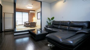 Uma sala de estar moderna com um sofá de couro preto, uma mesa de centro de vidro e um tapete de tatame.