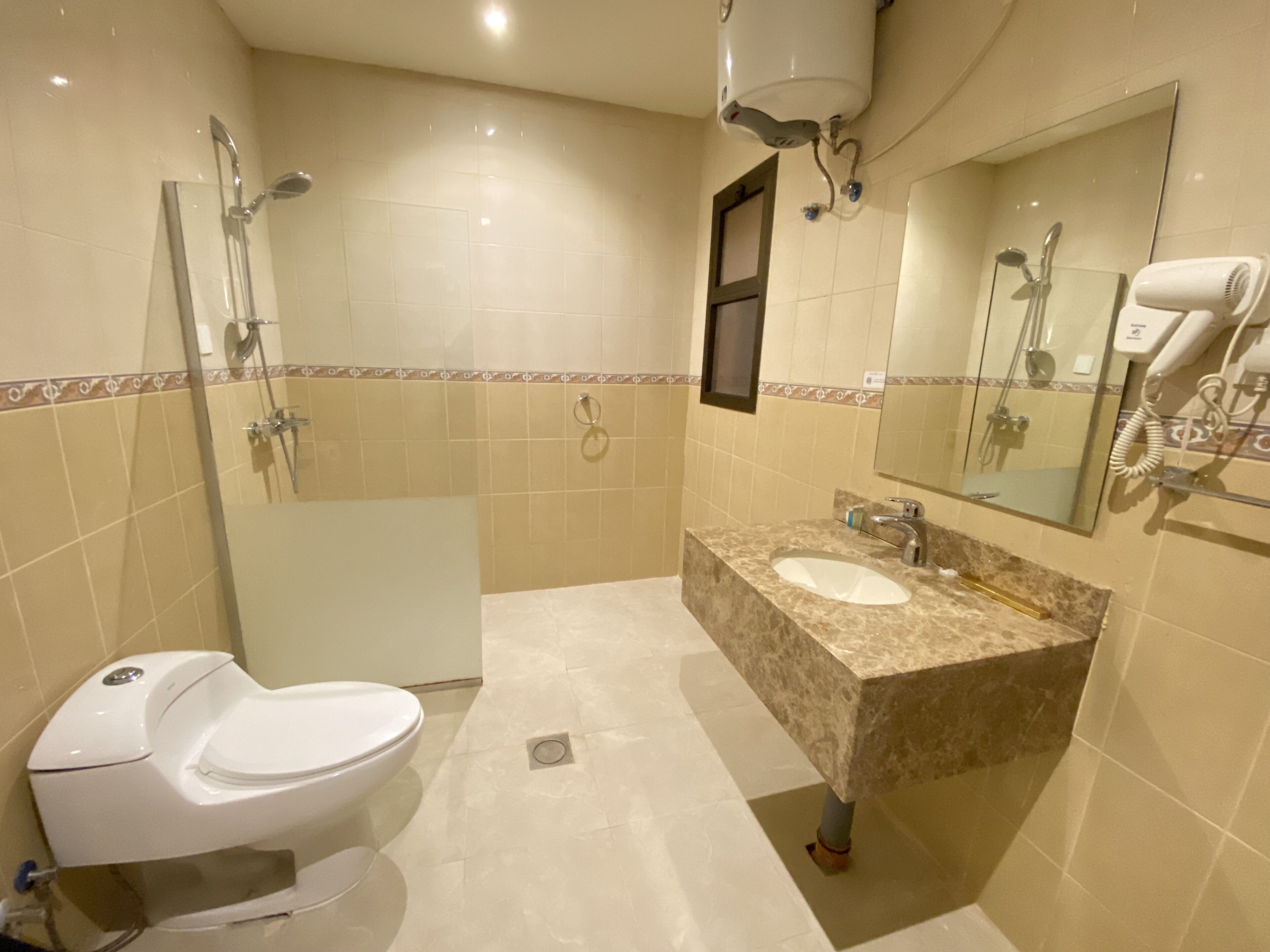 Casa de banho com sanita, lavatório, chuveiro e secador de cabelo.