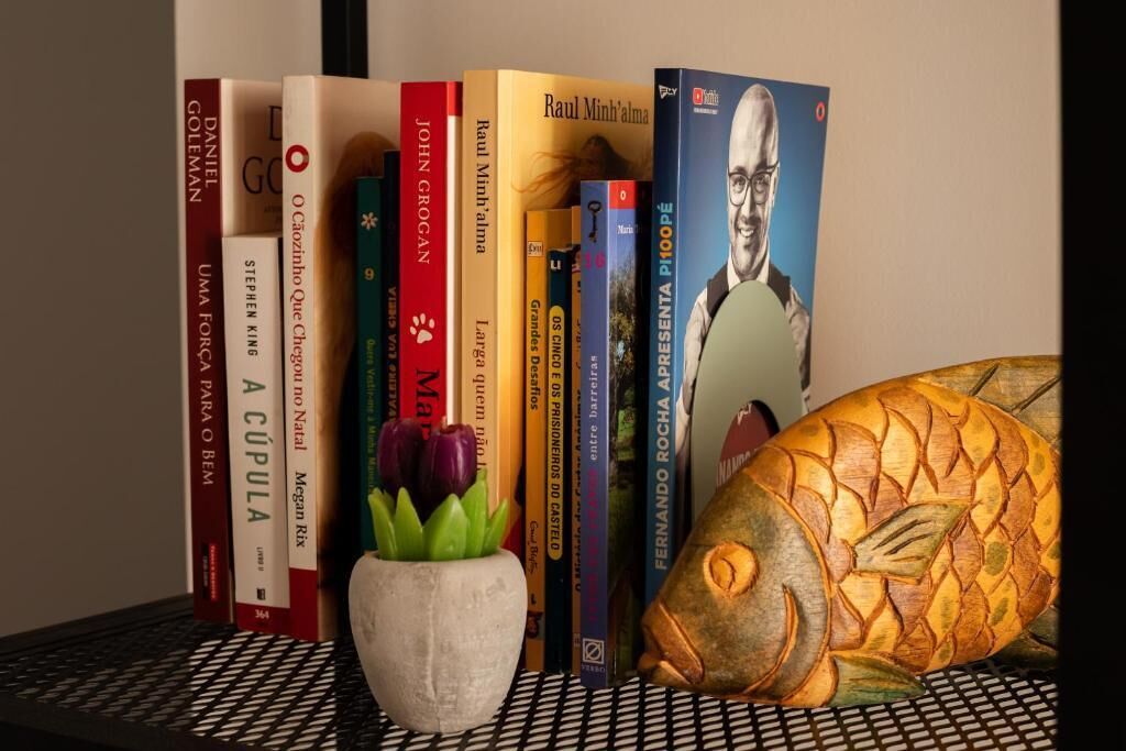 Uma estante com livros e uma escultura decorativa de peixe.