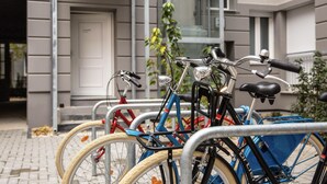 Uma fileira de bicicletas estacionadas em frente a um edifício com porta e janelas.
