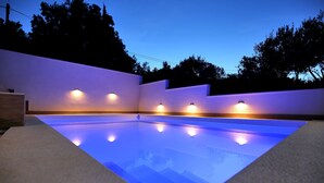Piscina com tonalidade azul, cercada por paredes com iluminação embutida.
