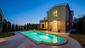 Uma casa moderna com piscina, varanda coberta e vista para a paisagem ao redor.