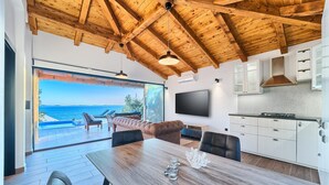 Cozinha moderna com armários brancos, televisão de tela plana e teto de madeira.