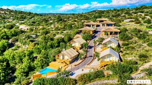 Um terreno em encosta com vários chalés de madeira, uma piscina e uma estrada sinuosa.